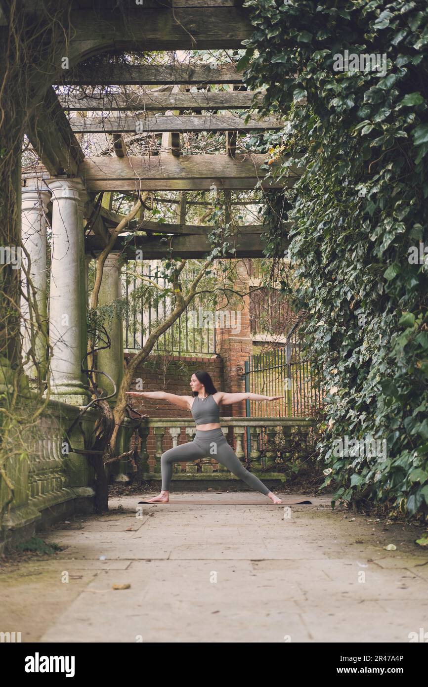 A young adult female new yoga teacher in warrior two pose training ...