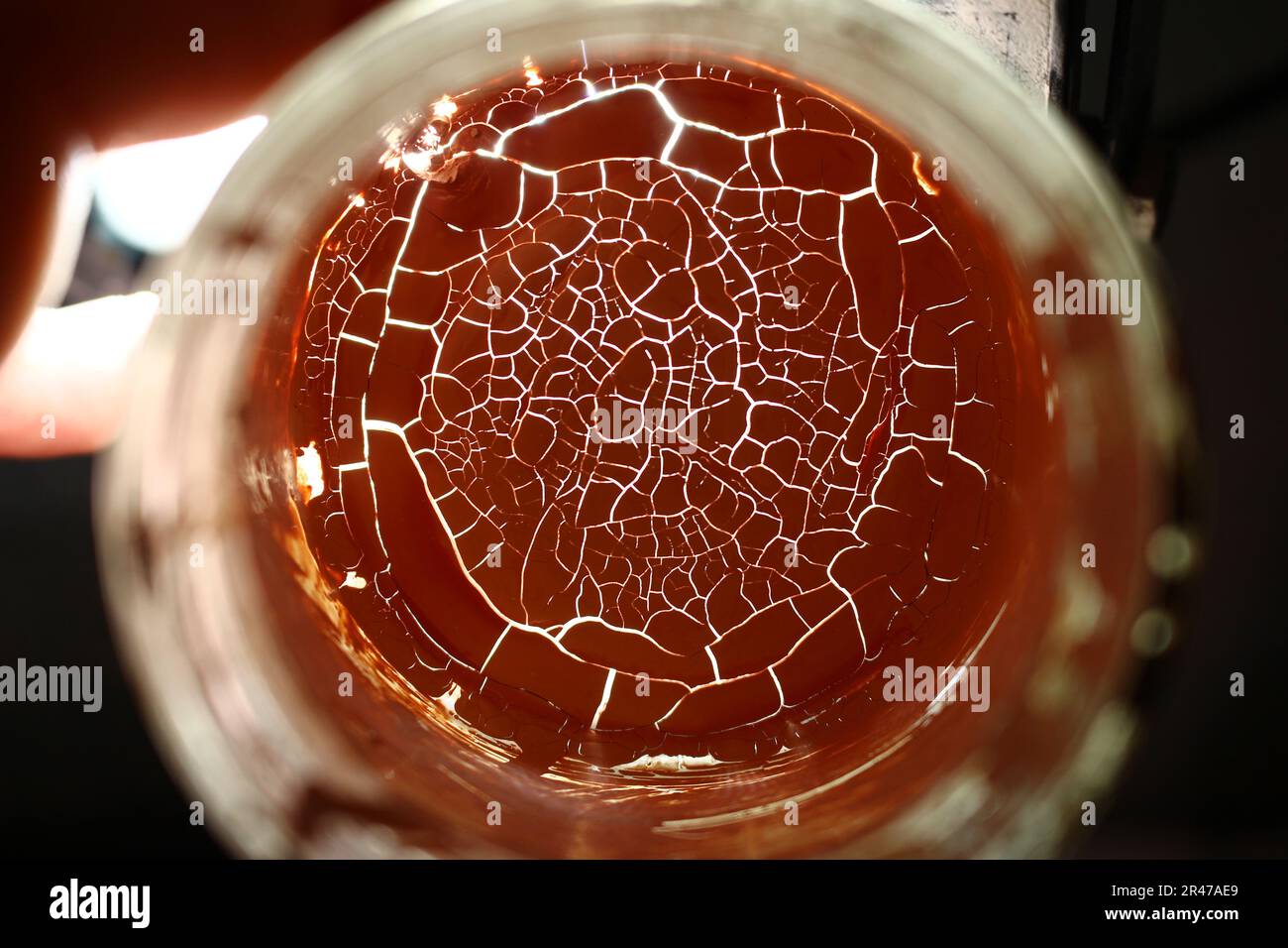 The texture of cracked dried paint at the bottom of a glass jar to the ...