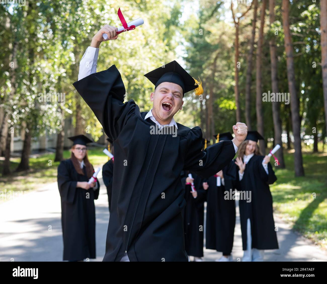 Happy young caucasian man celebrating graduation. Crowd of students ...