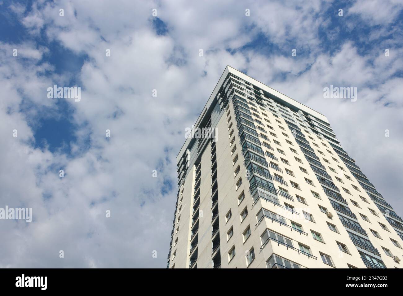 High-rise building view from below against a blue sky with white clouds ...