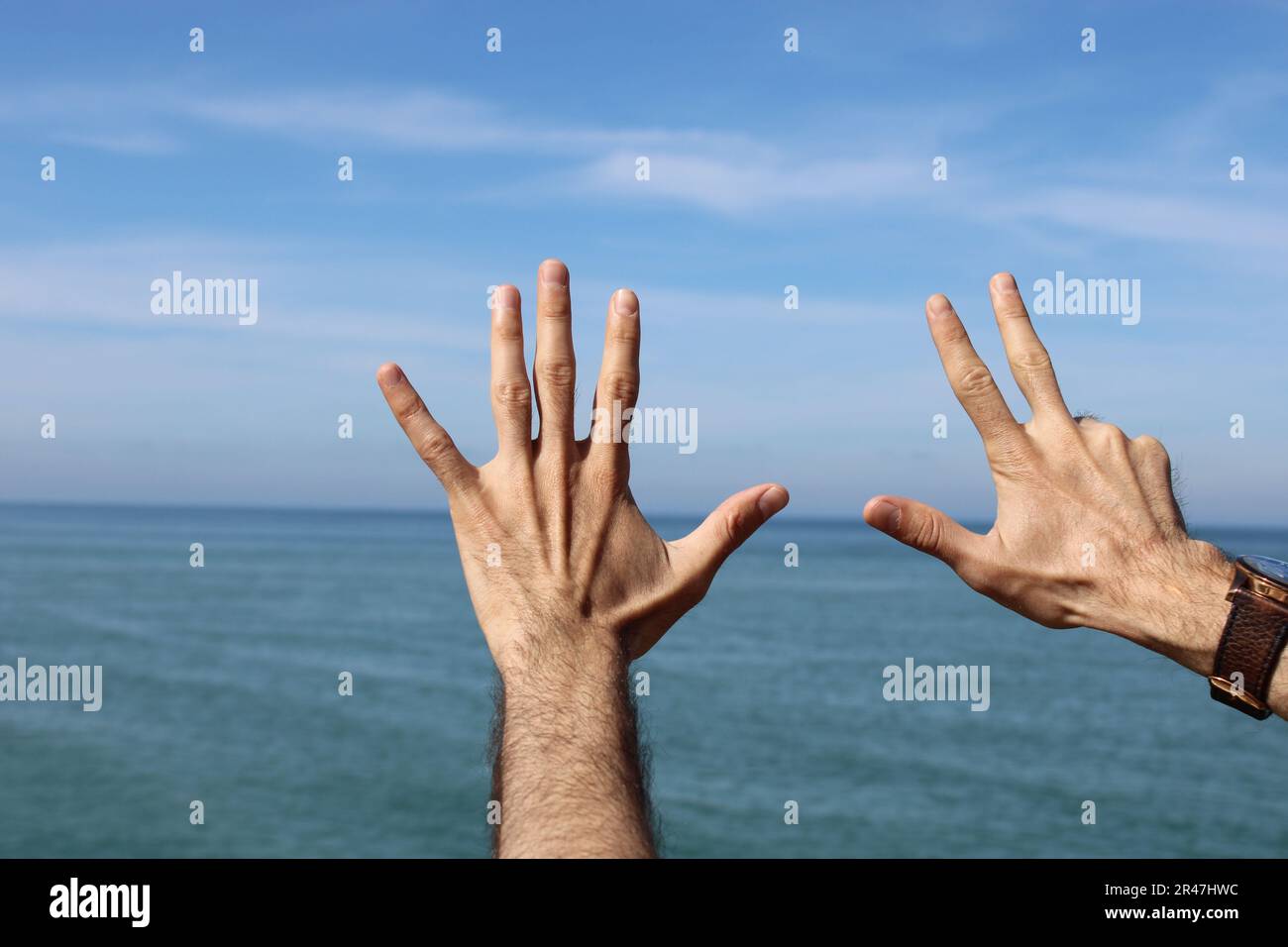 Hand doing,showing number gesture symbol eight on blue summer sky ...