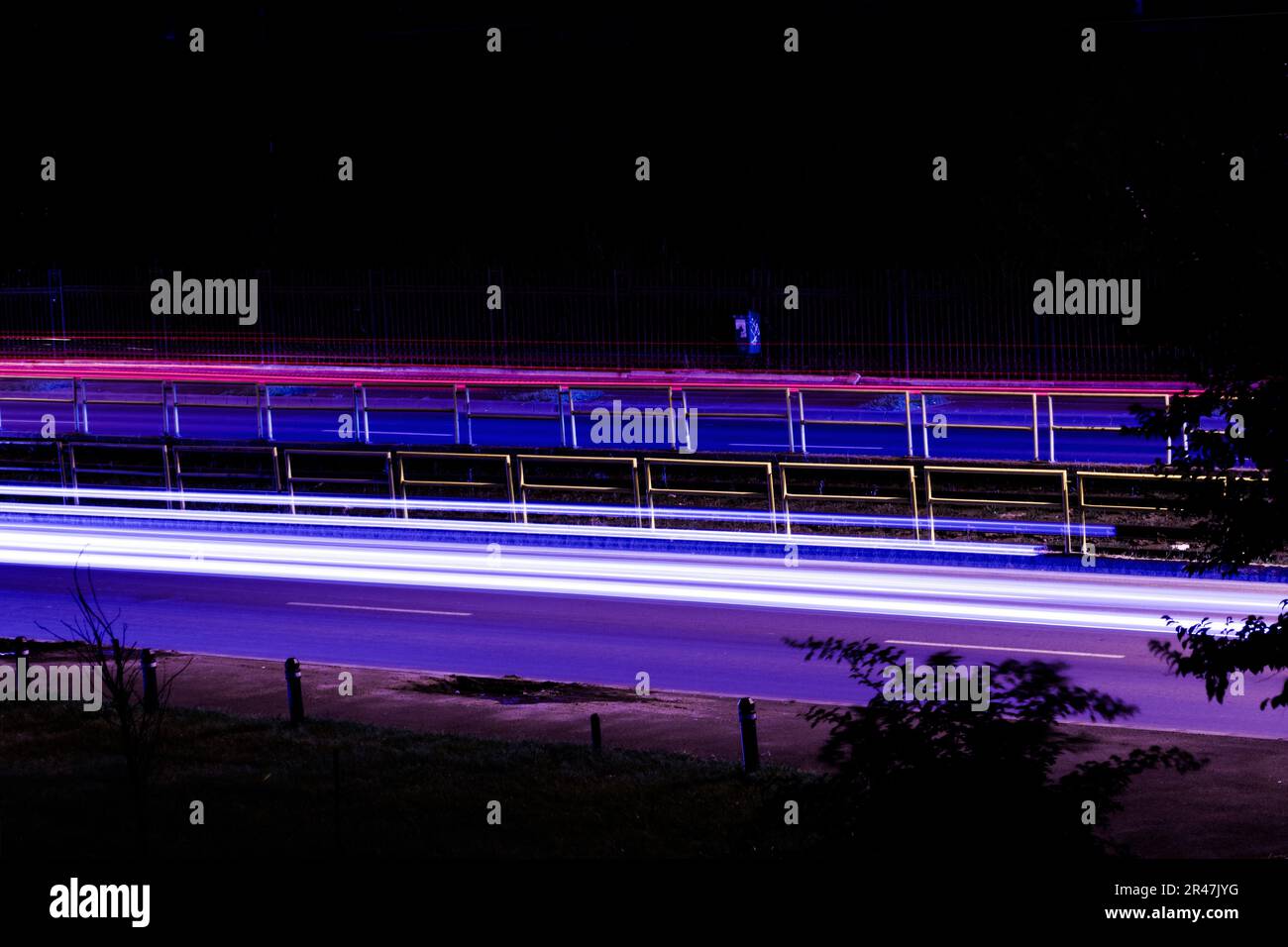 Colorful light trails streak across a night sky, illuminated by cars ...