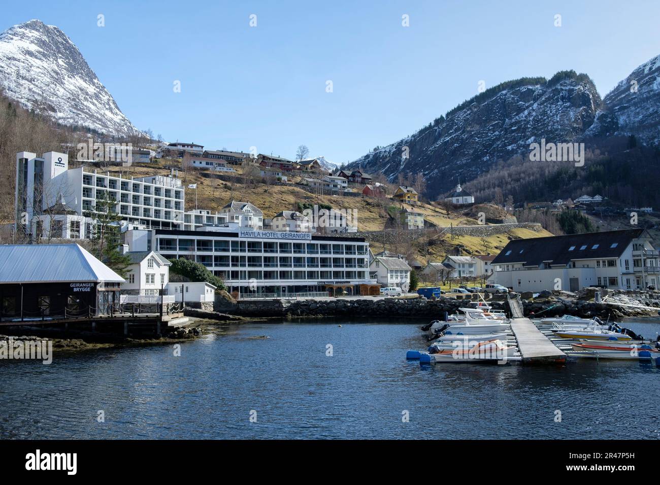 A fleet of boats is docked at the harbor of a marina, with jagged ...