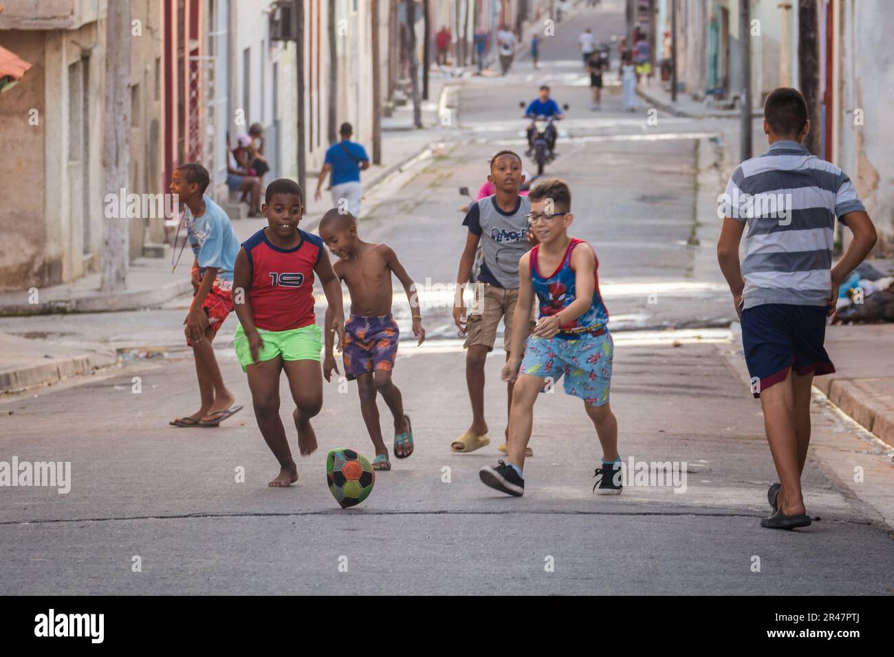 A group of happy Cuban children playing a lively game of ball in an ...