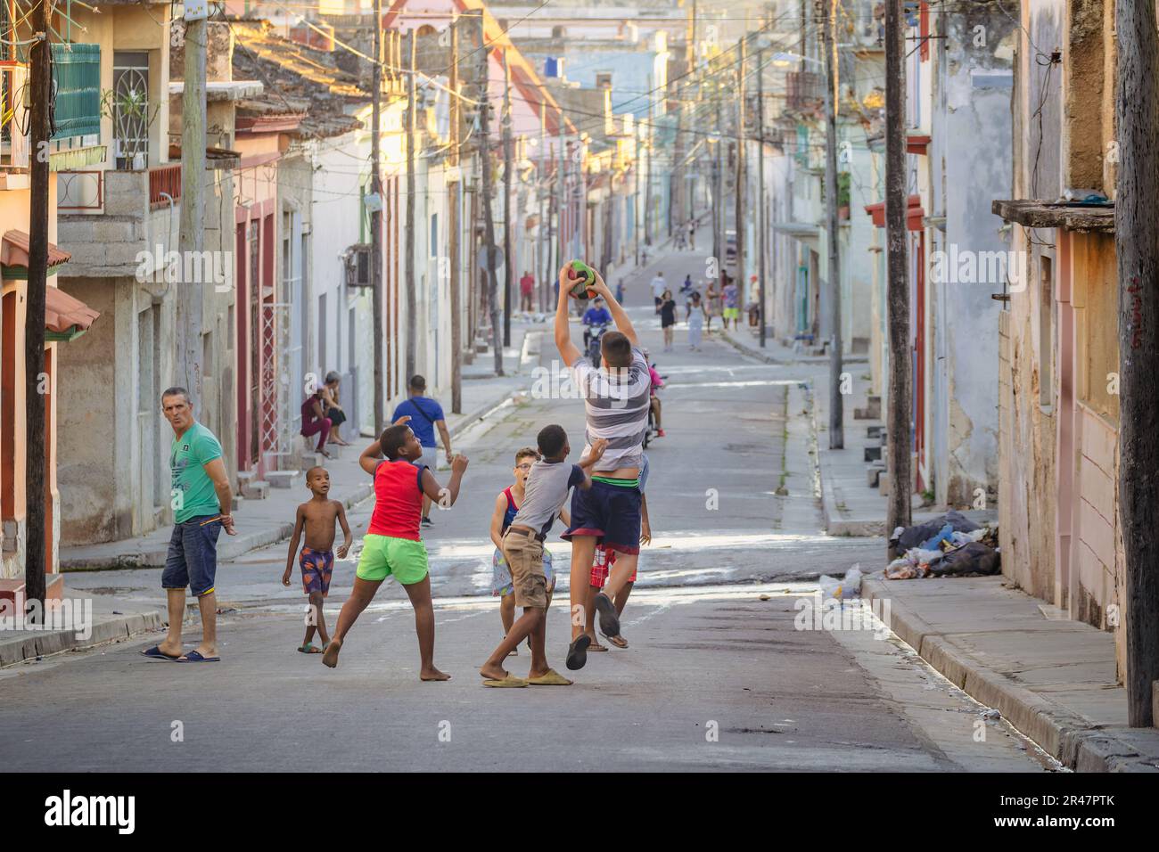 A group of happy Cuban children playing a lively game of ball in an ...