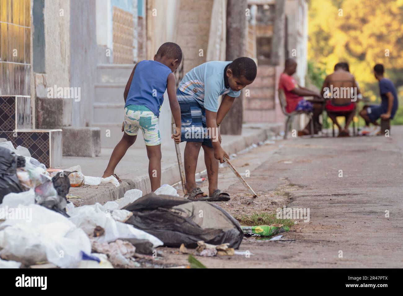Two young children sitting on the sidewalk and cleaning up garbage ...