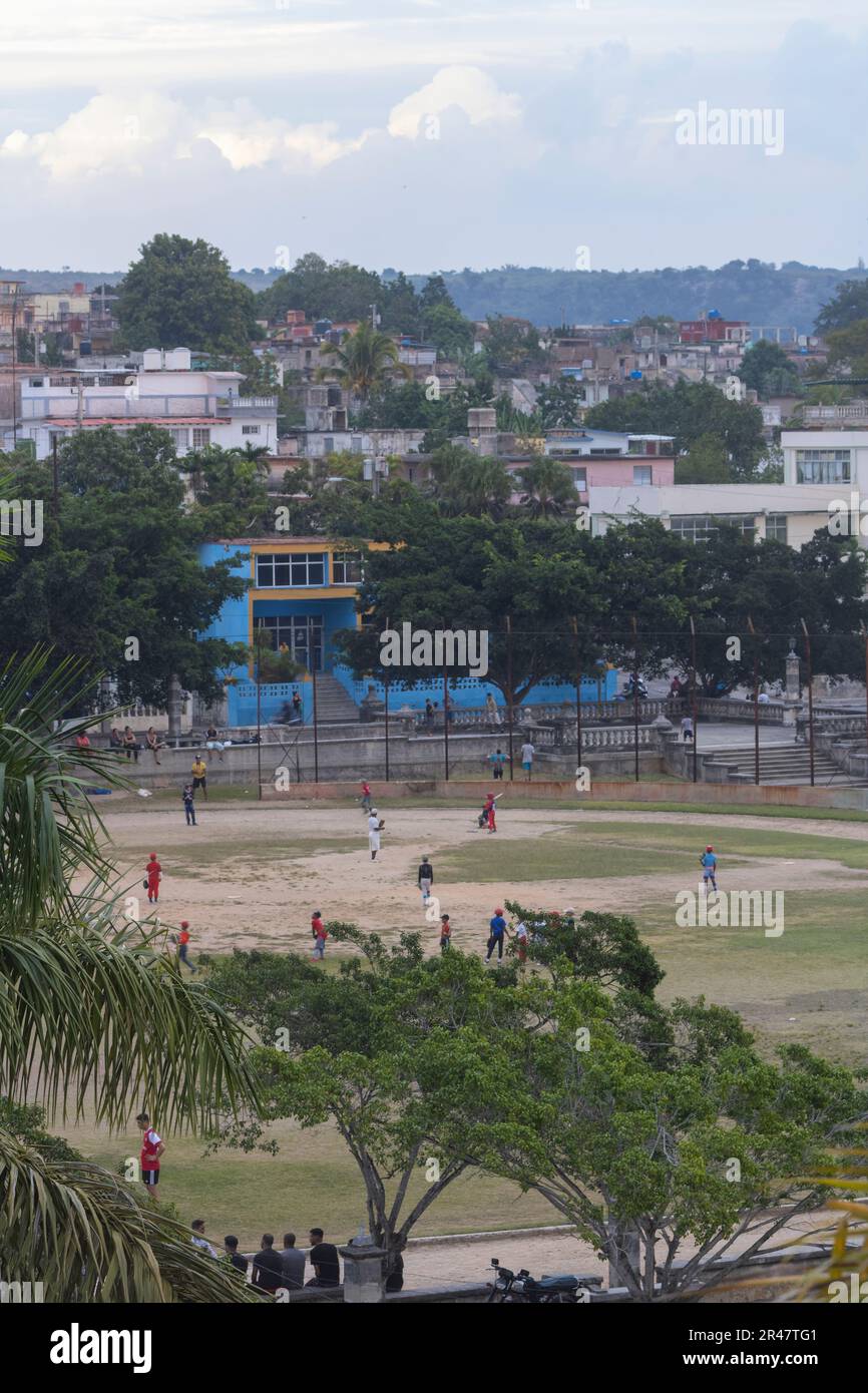 A group of children playing baseball in an open field surrounded by ...