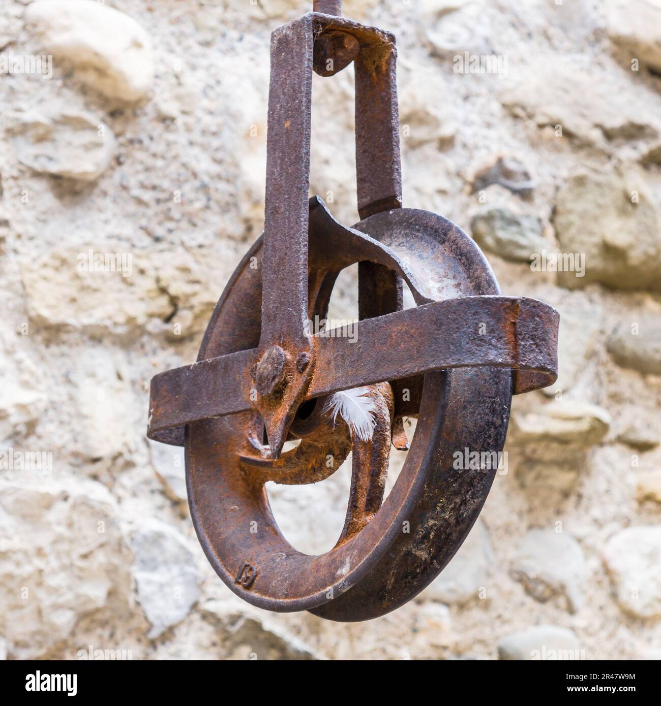 A rusty pull chain attached to an aged stone wall in an outdoor setting ...