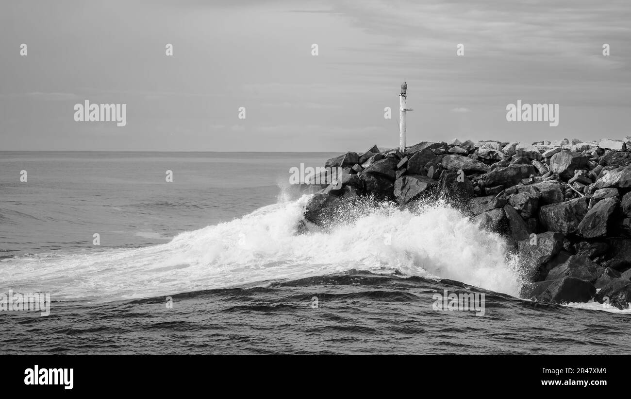 A large ocean wave crashing against a large rock wall, with the expanse ...