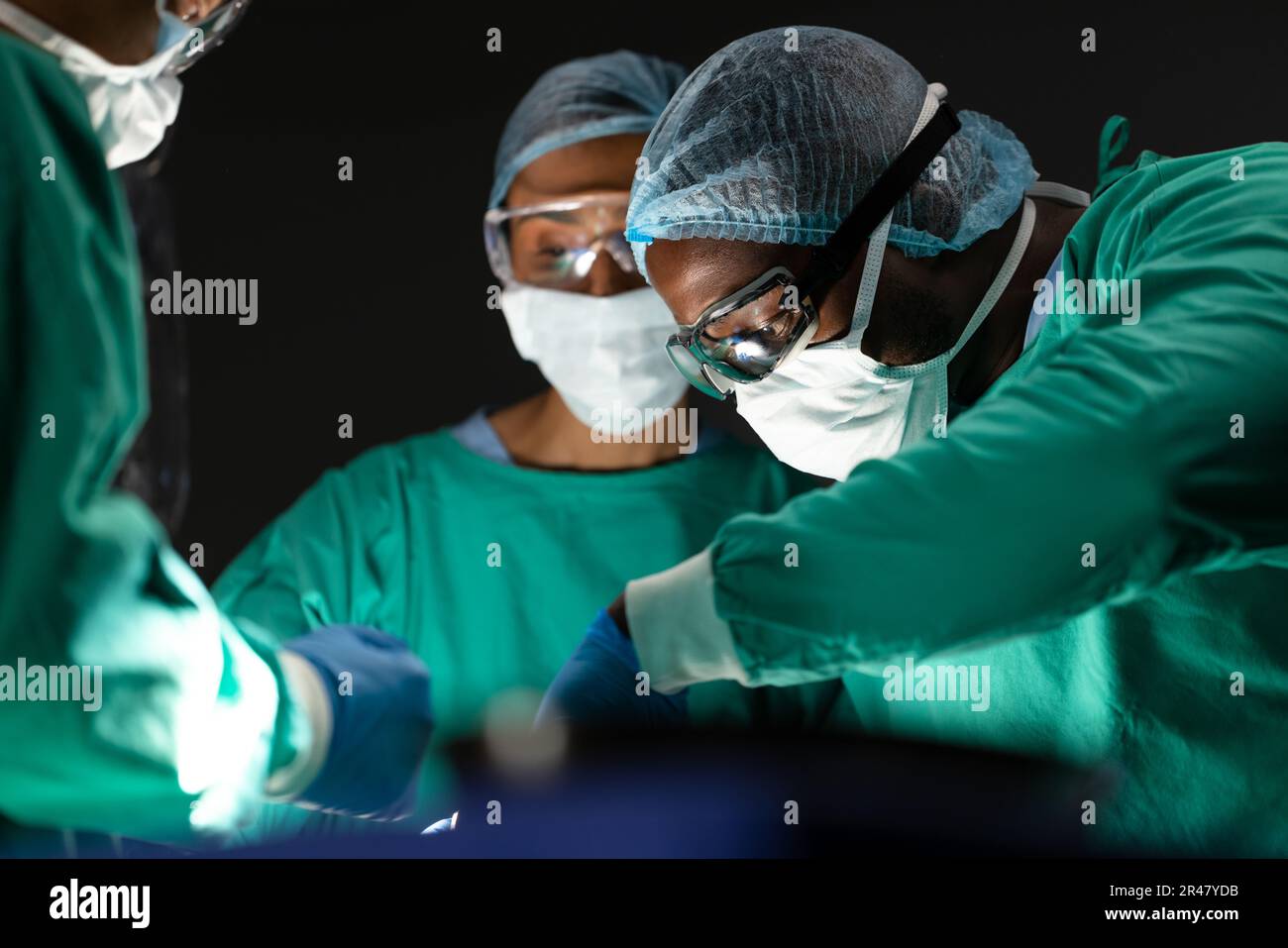 Diverse surgeons operating on patient in operating theatre at hospital ...