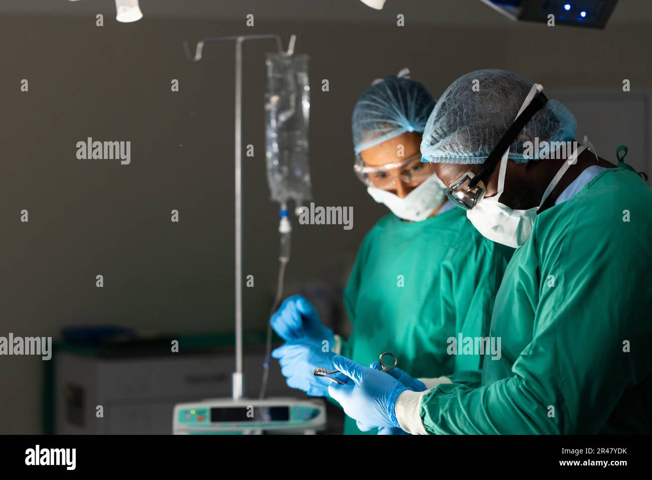 Diverse male and female surgeon looking at surgical tool in operating ...