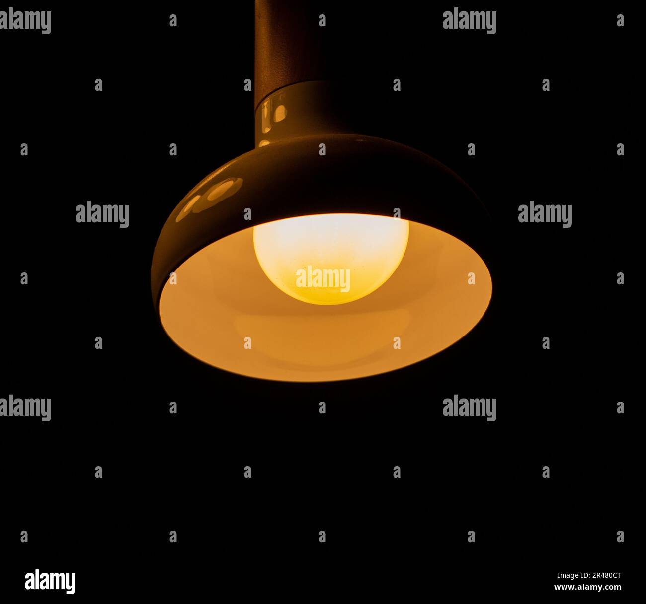 A bright lamp light illuminates a dark room, creating a warm, inviting ...