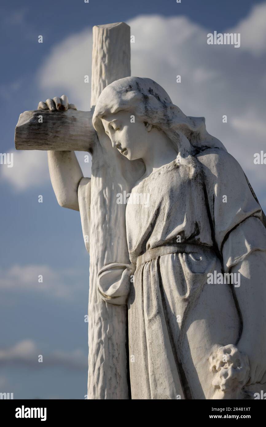 An angelic figure stands against a serene sky as they hold a cross in ...