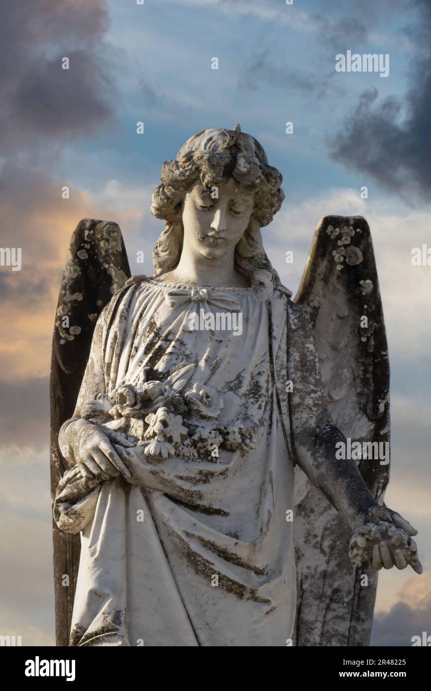 A beautiful angelic statue stands in silhouette in front of a dramatic ...