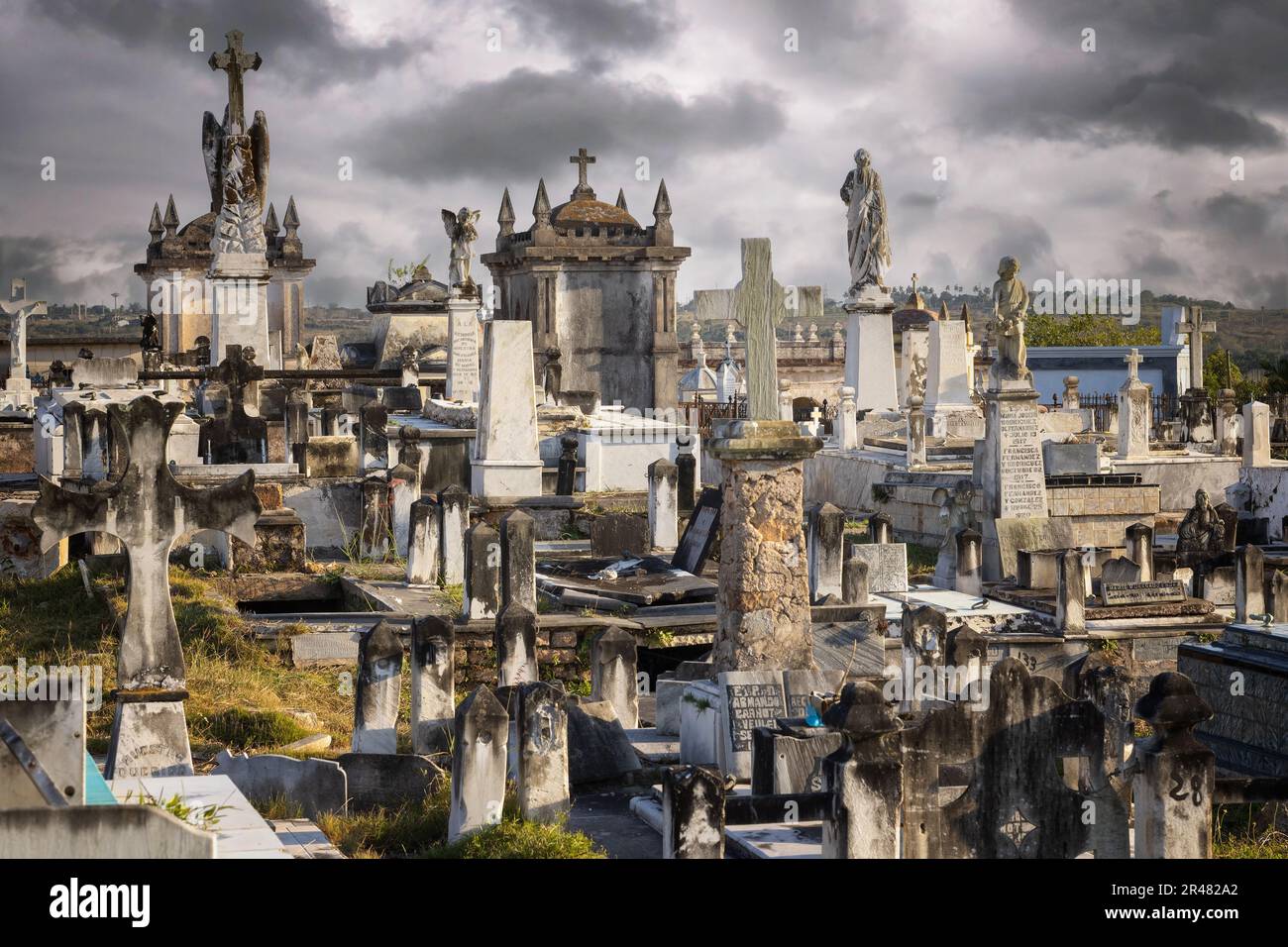 A peaceful cemetery scene featuring a variety of ornate and rustic tombstones and buildings ...