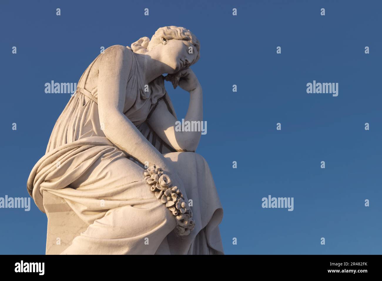 A marble statue of a female figure atop a cylindrical stone pillar ...