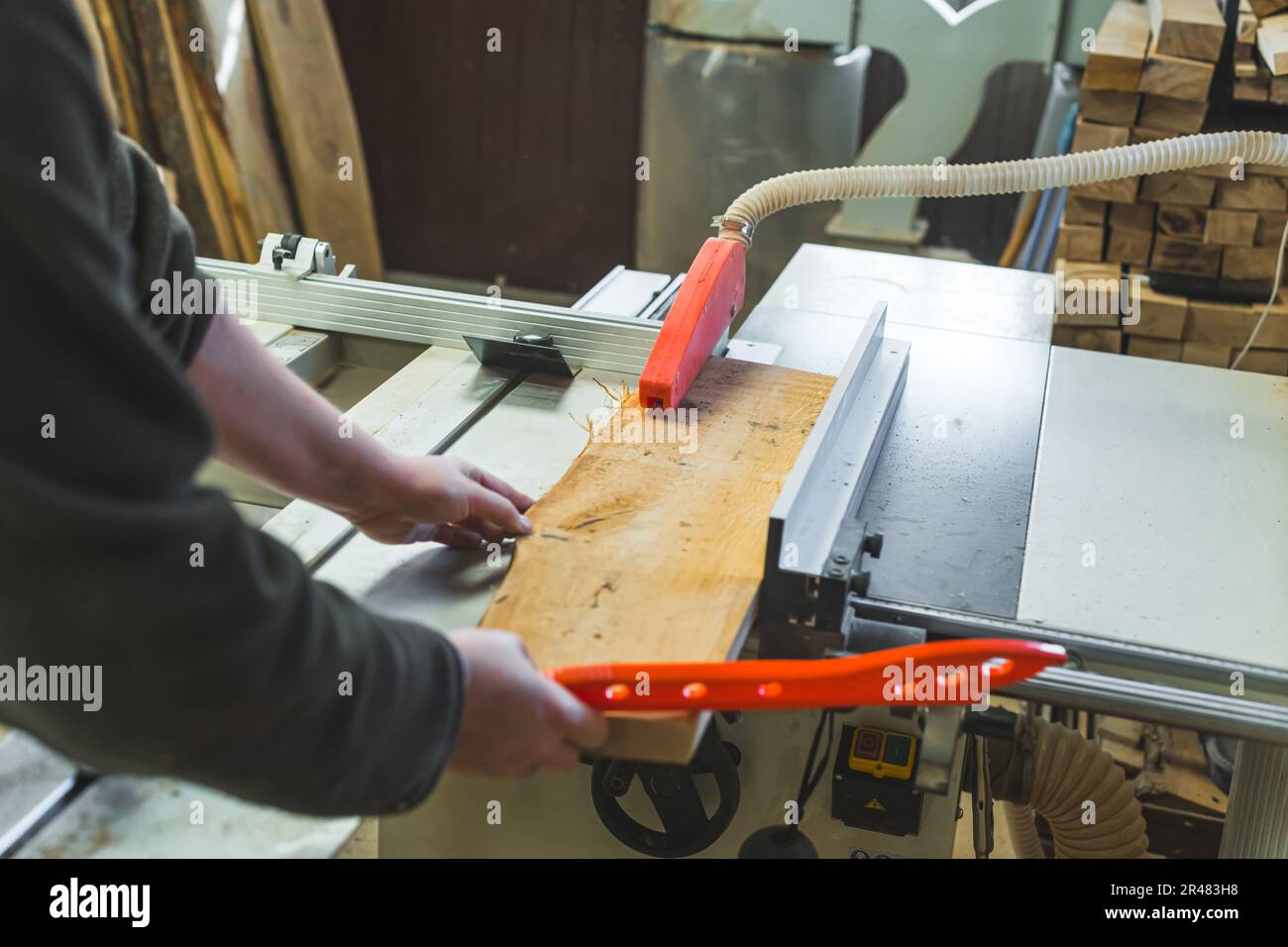 Carpenter using table saw blade to cut wooden plank while sliding it on ...