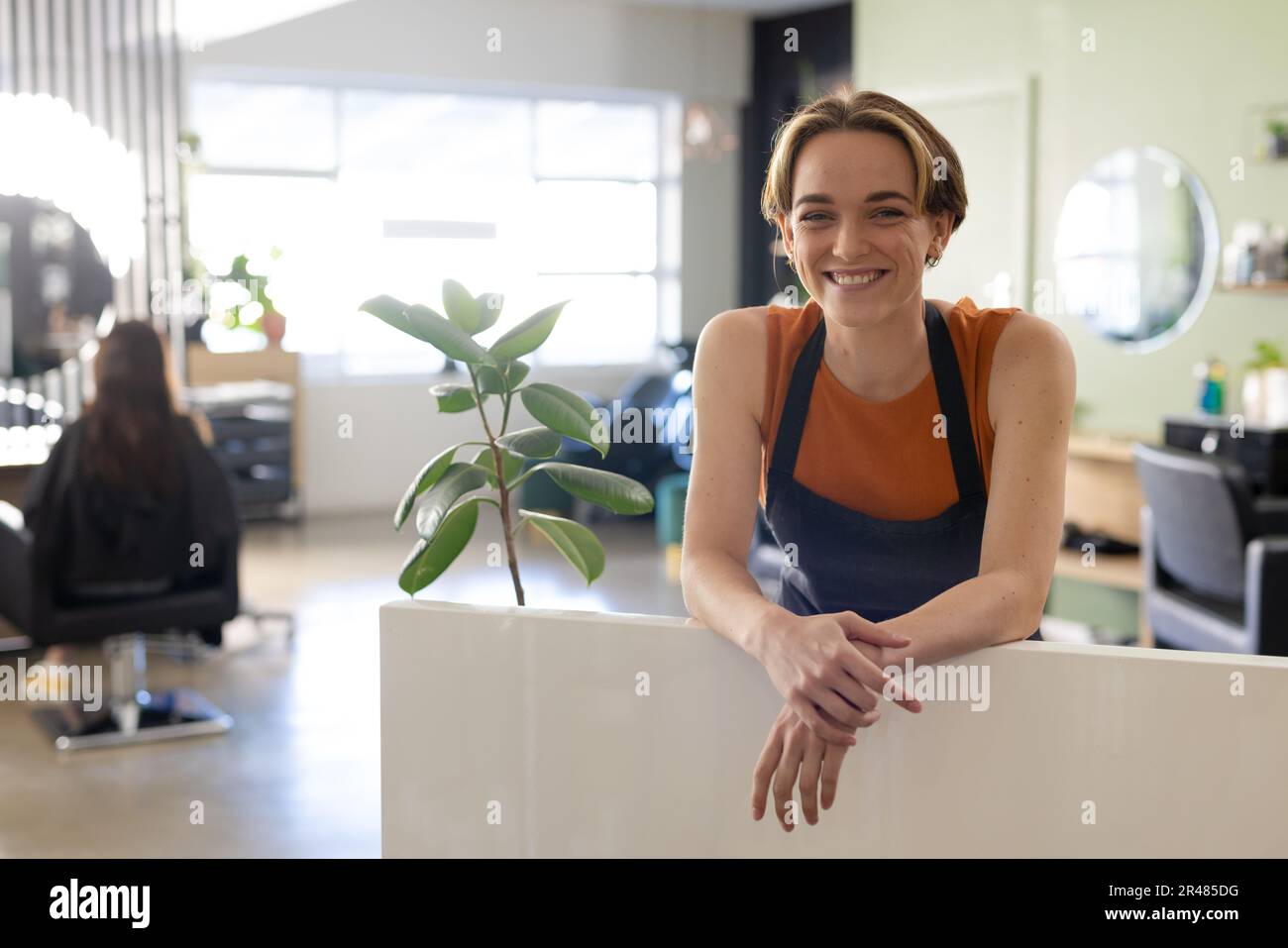 Portrait of smiling caucasian female hairdresser at reception desk in ...