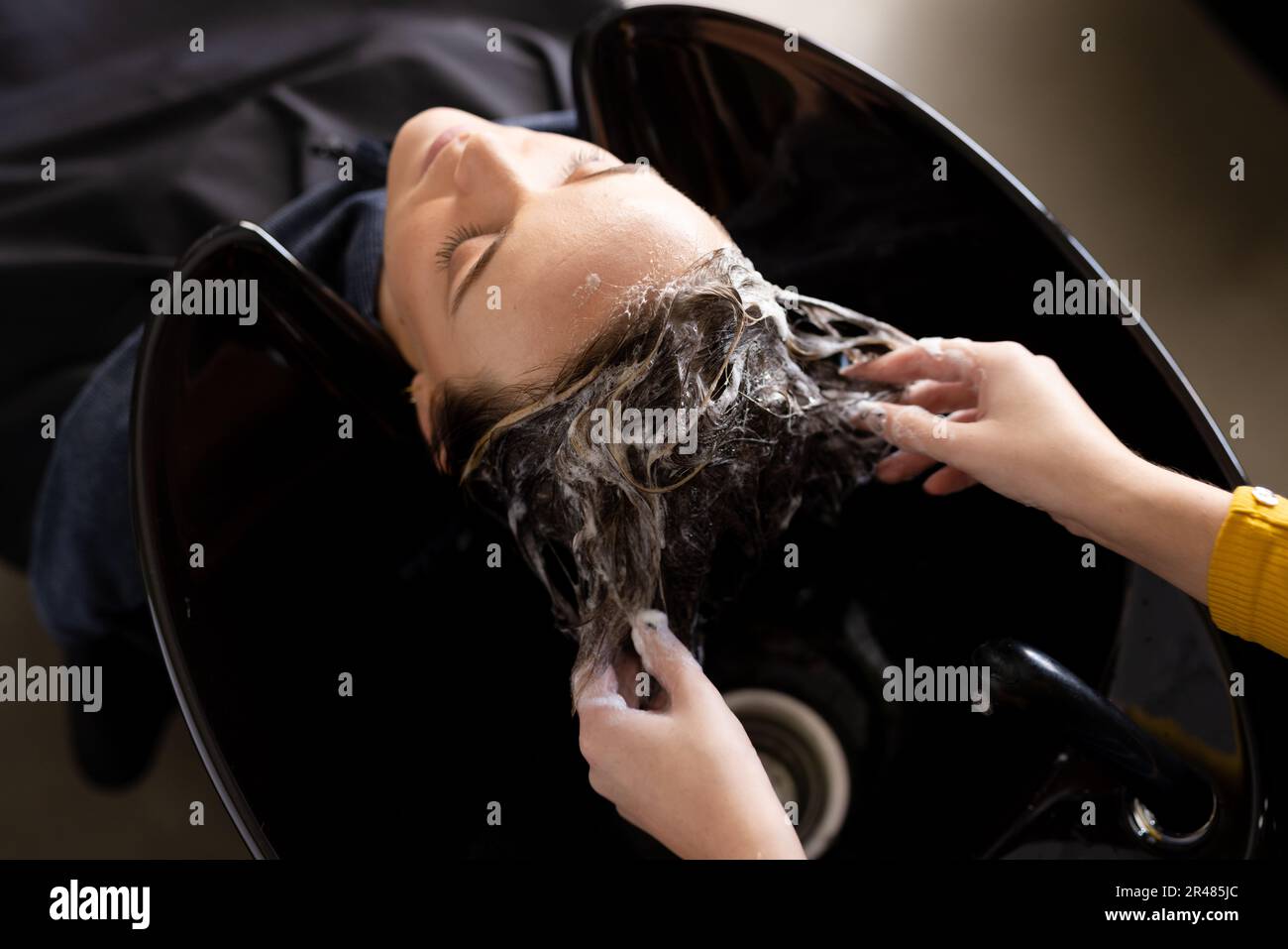Hands of caucasian female hairdresser washing hair of relaxed female ...