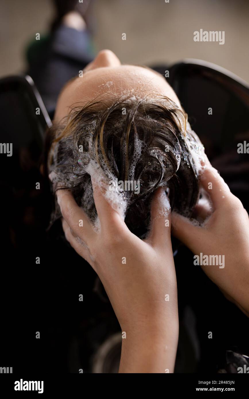 Hands of caucasian female hairdresser washing hair of relaxed female ...