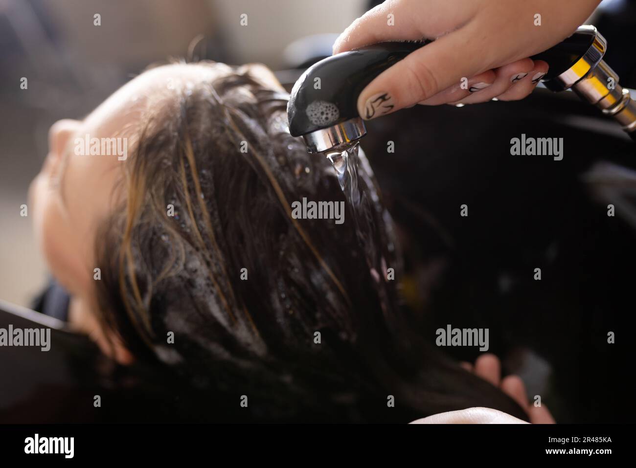 Hand of caucasian female hairdresser washing hair of relaxed female ...