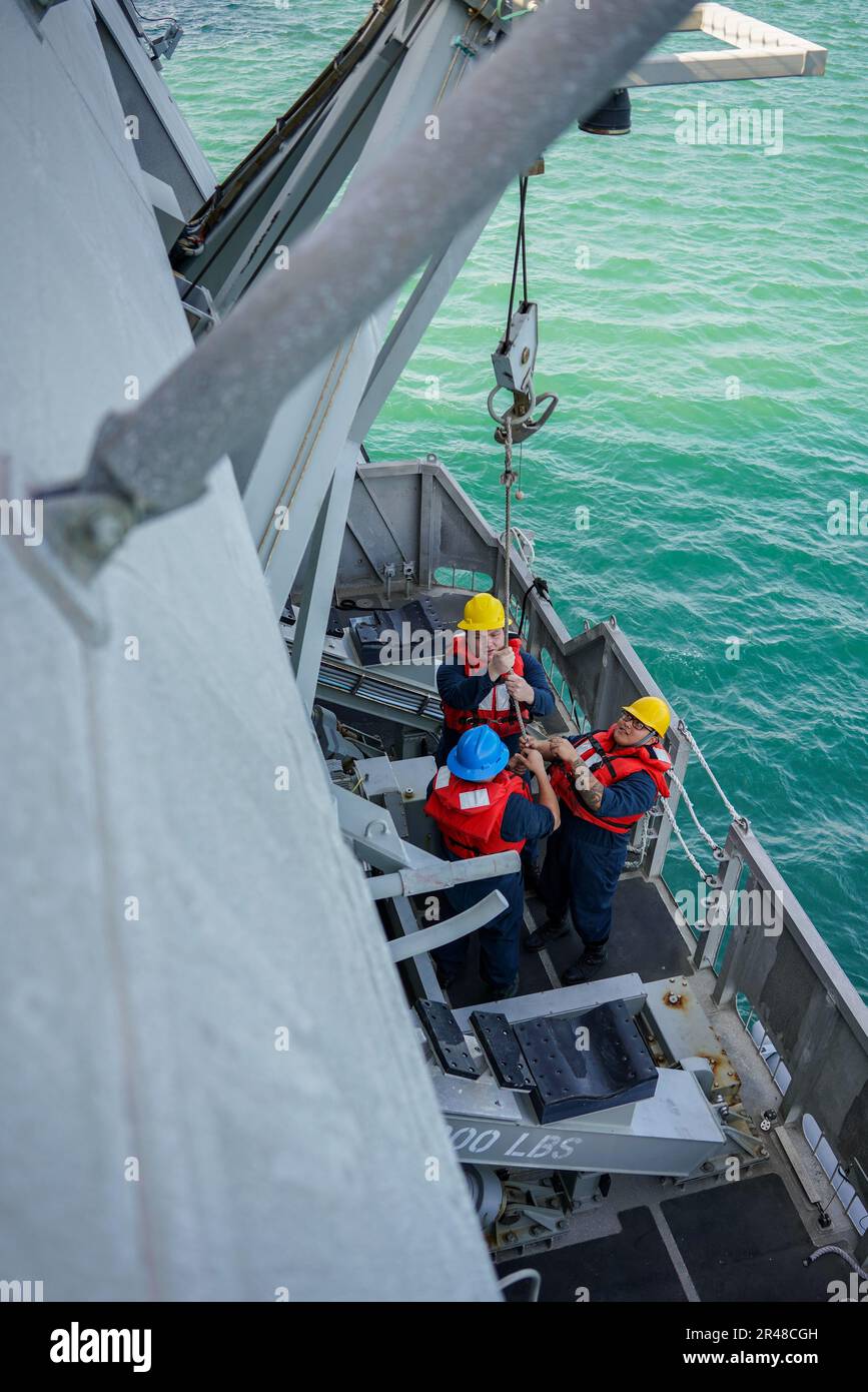SINGAPORE (Mar. 13, 2023) Sailors manually lower the davit hook for ...