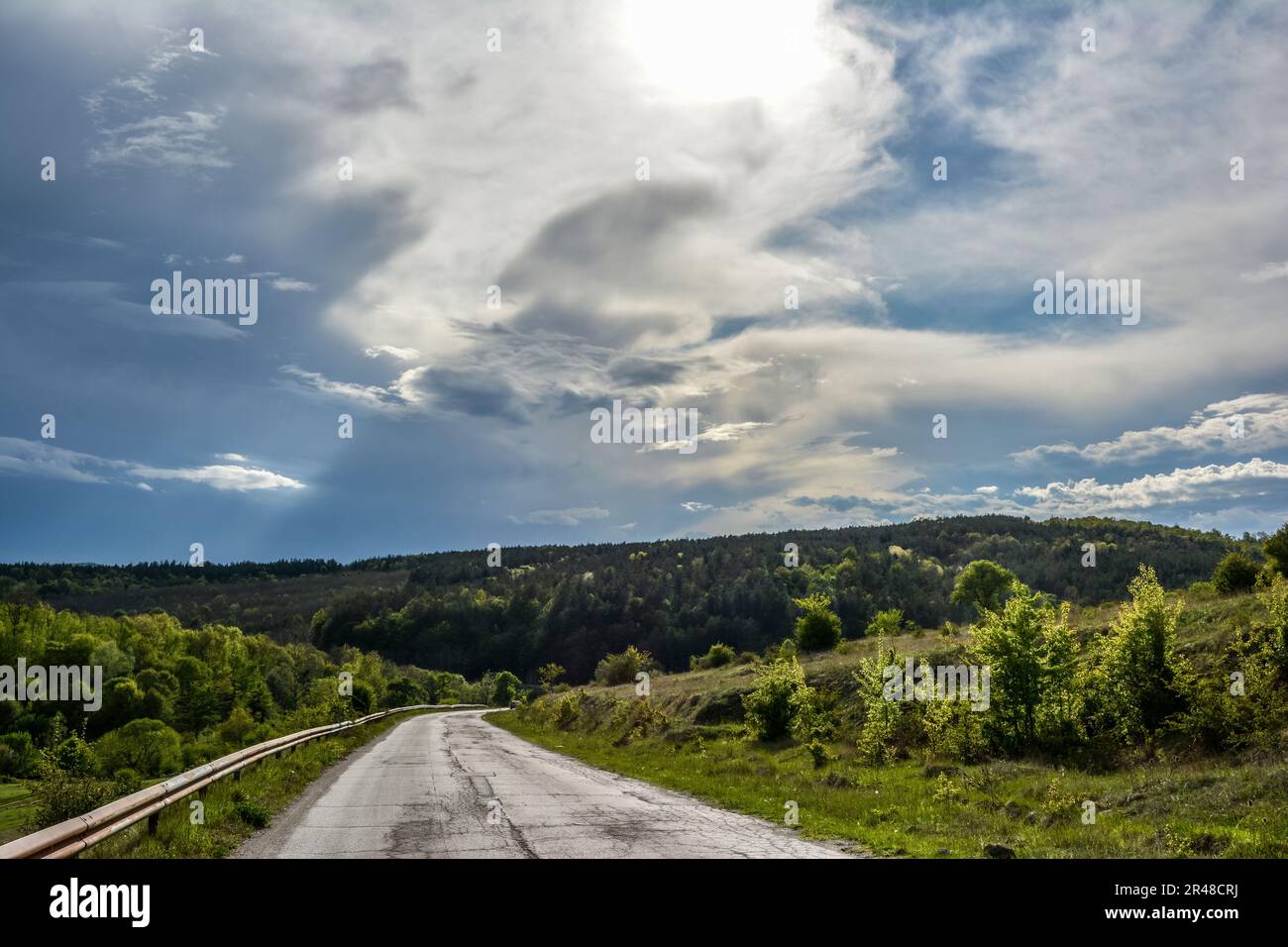 A scenic view of an empty road stretching across a sunny landscape ...