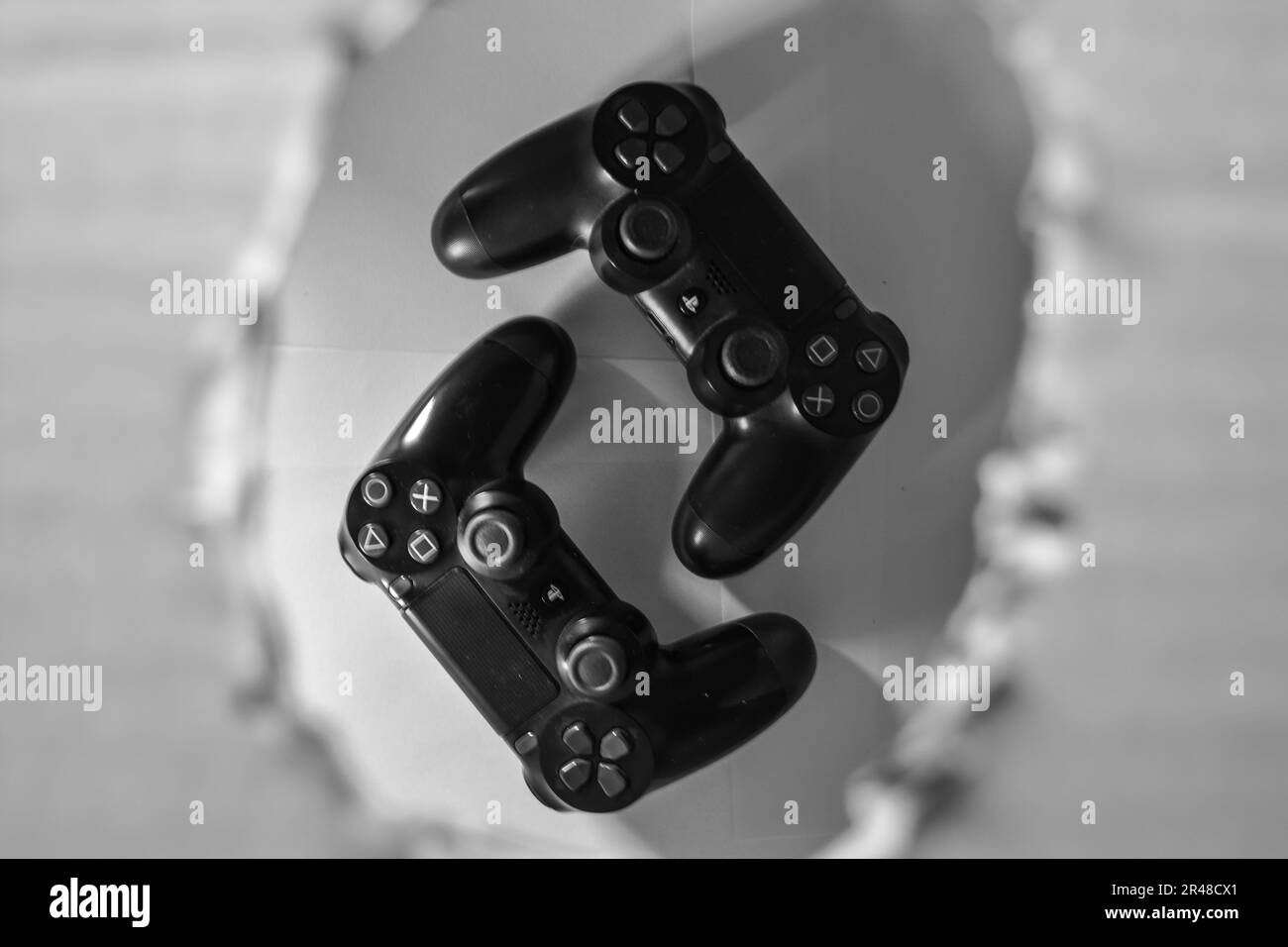 A grayscale shot of two standard video game controllers lying side by ...