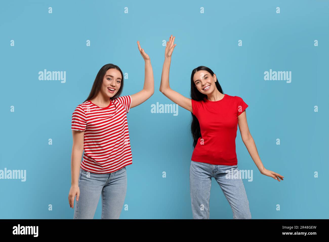 Women giving high five on light blue background Stock Photo - Alamy