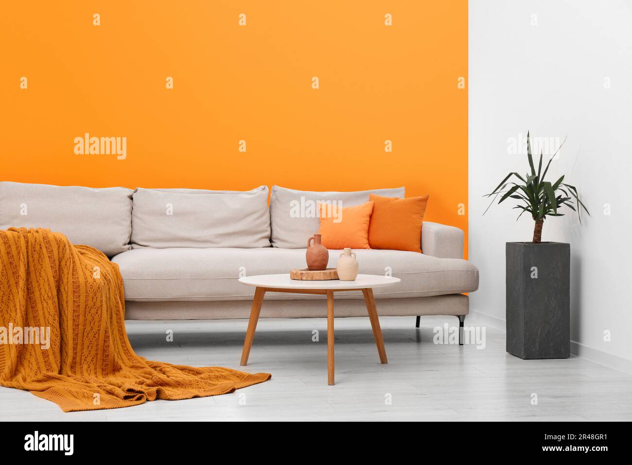 Stylish sofa and coffee table in room with orange walls. Interior ...