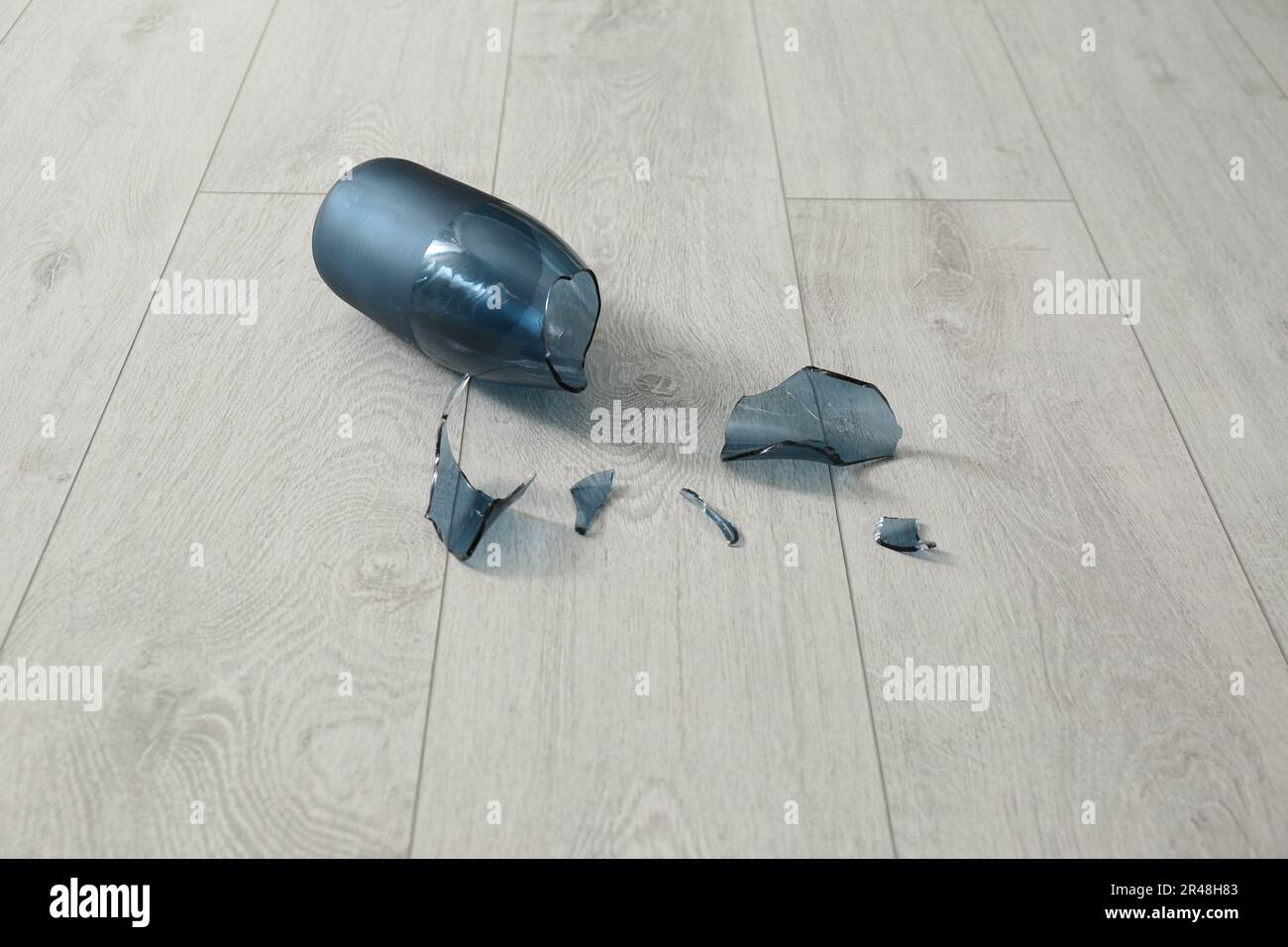 Broken blue glass vase on wooden floor Stock Photo - Alamy