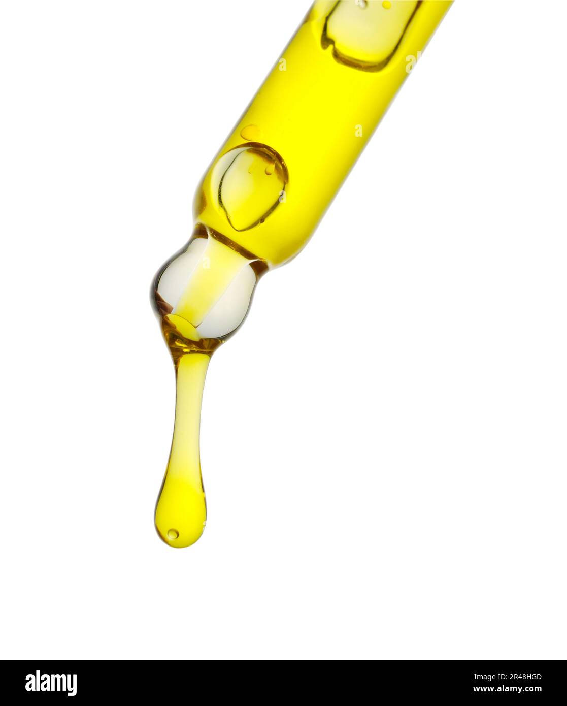 Dripping yellow facial serum from pipette on white background, closeup ...