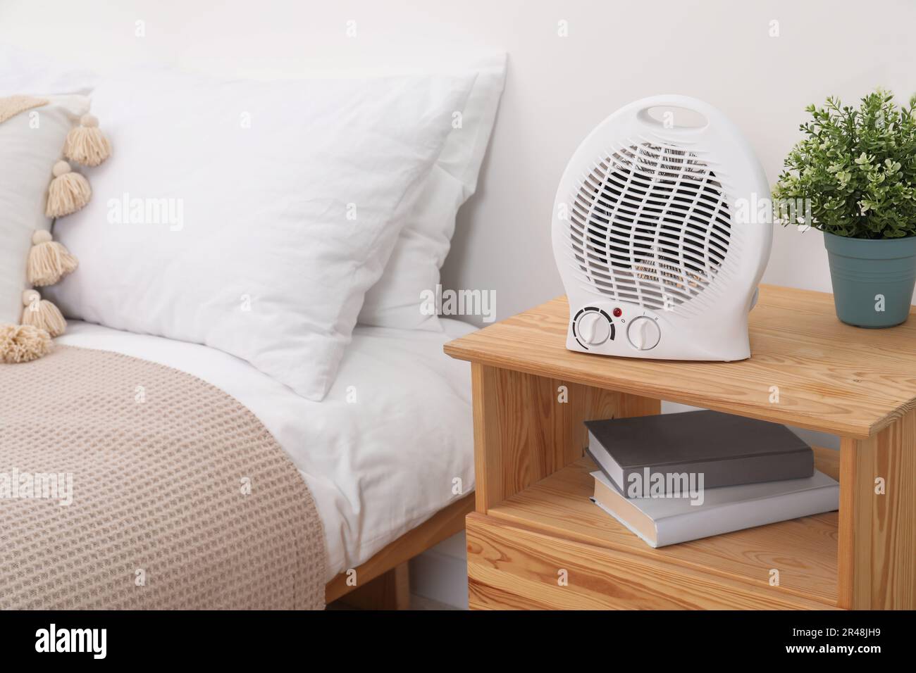 Modern electric fan heater on bedside table indoors Stock Photo - Alamy