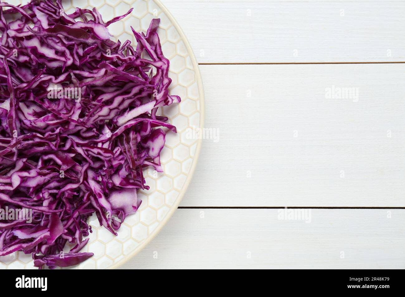 Plate with shredded fresh red cabbage on white wooden table, top view ...