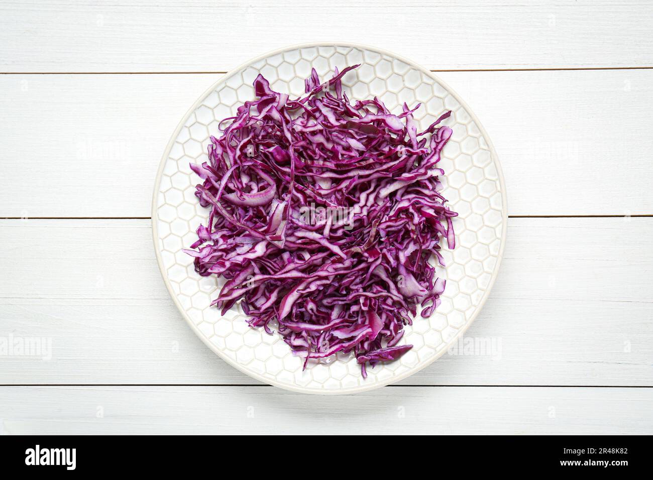 Plate with shredded fresh red cabbage on white wooden table, top view ...
