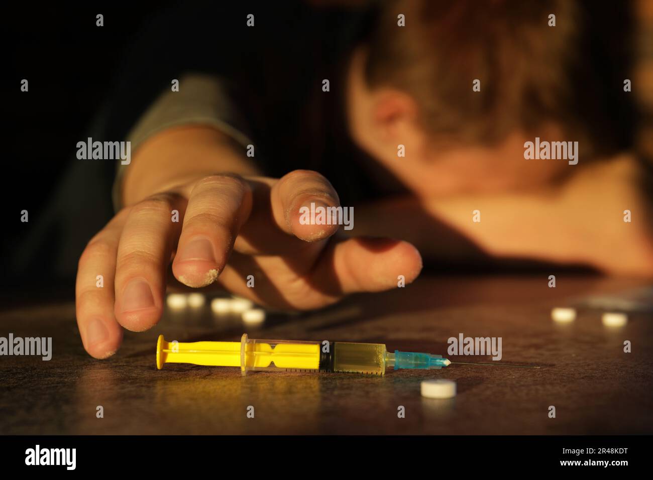 Addicted man reaching to drugs at grey textured table, focus on syringe ...