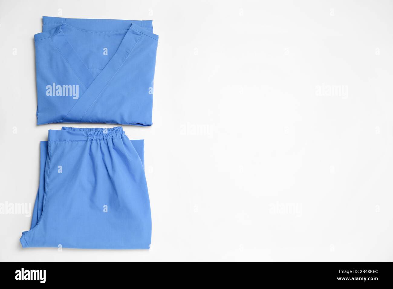 Light blue medical uniforms on white background, flat lay. Space for ...