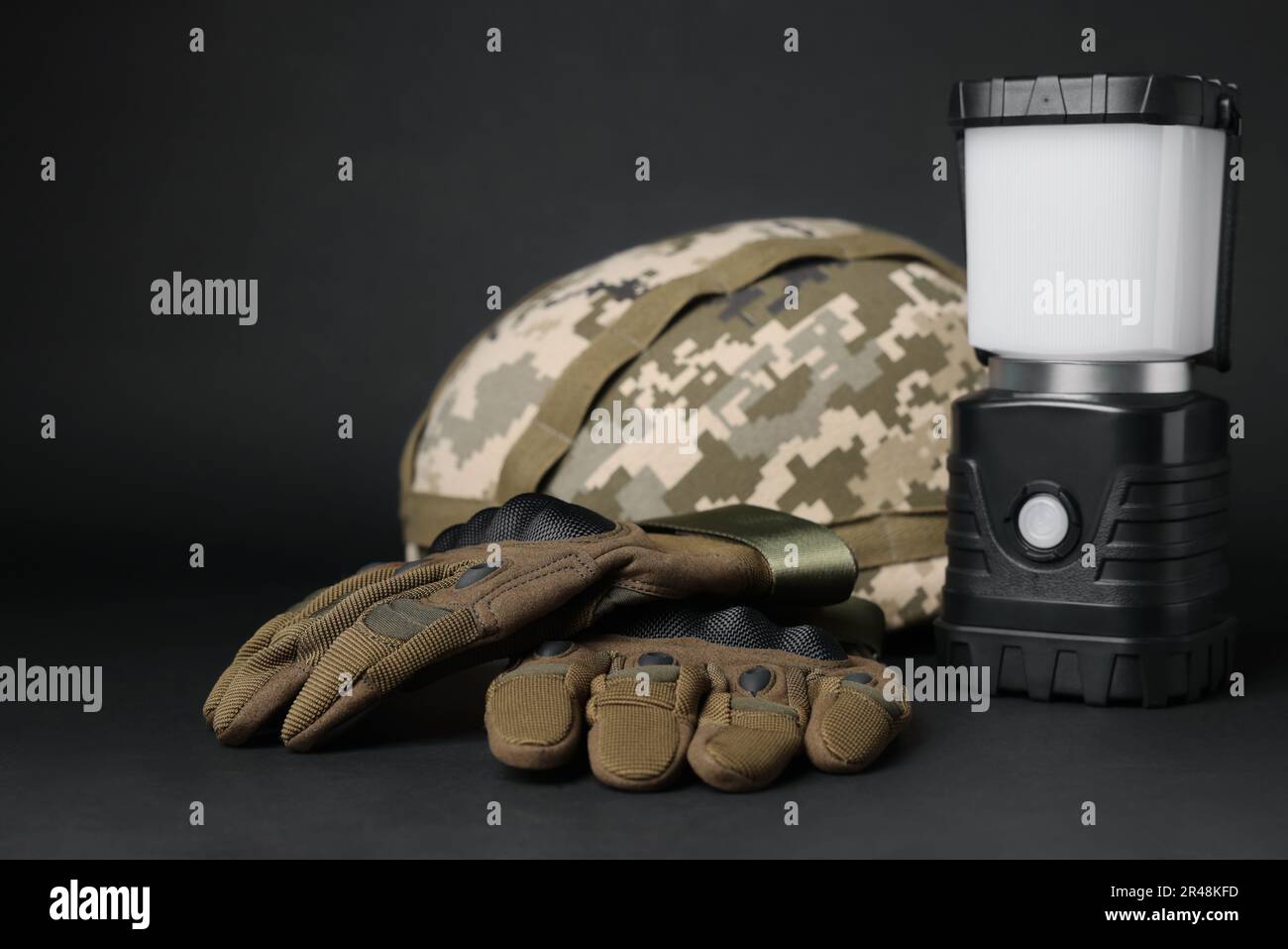 Tactical gloves, helmet and camping lantern on black background ...