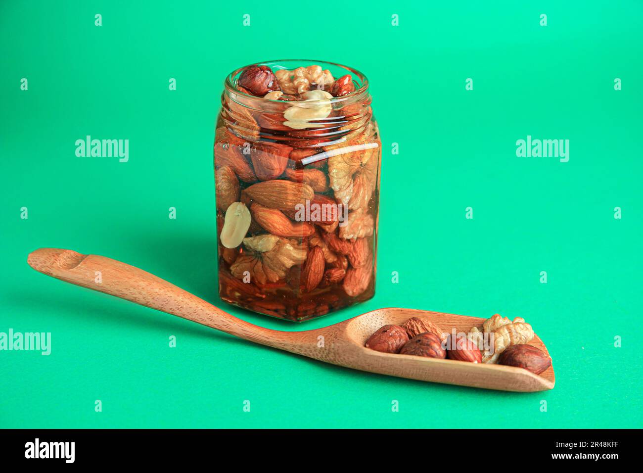 Different tasty nuts with honey on green background Stock Photo - Alamy