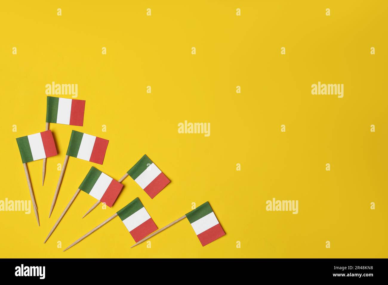 Small paper flags of Italy on yellow background, flat lay. Space for ...