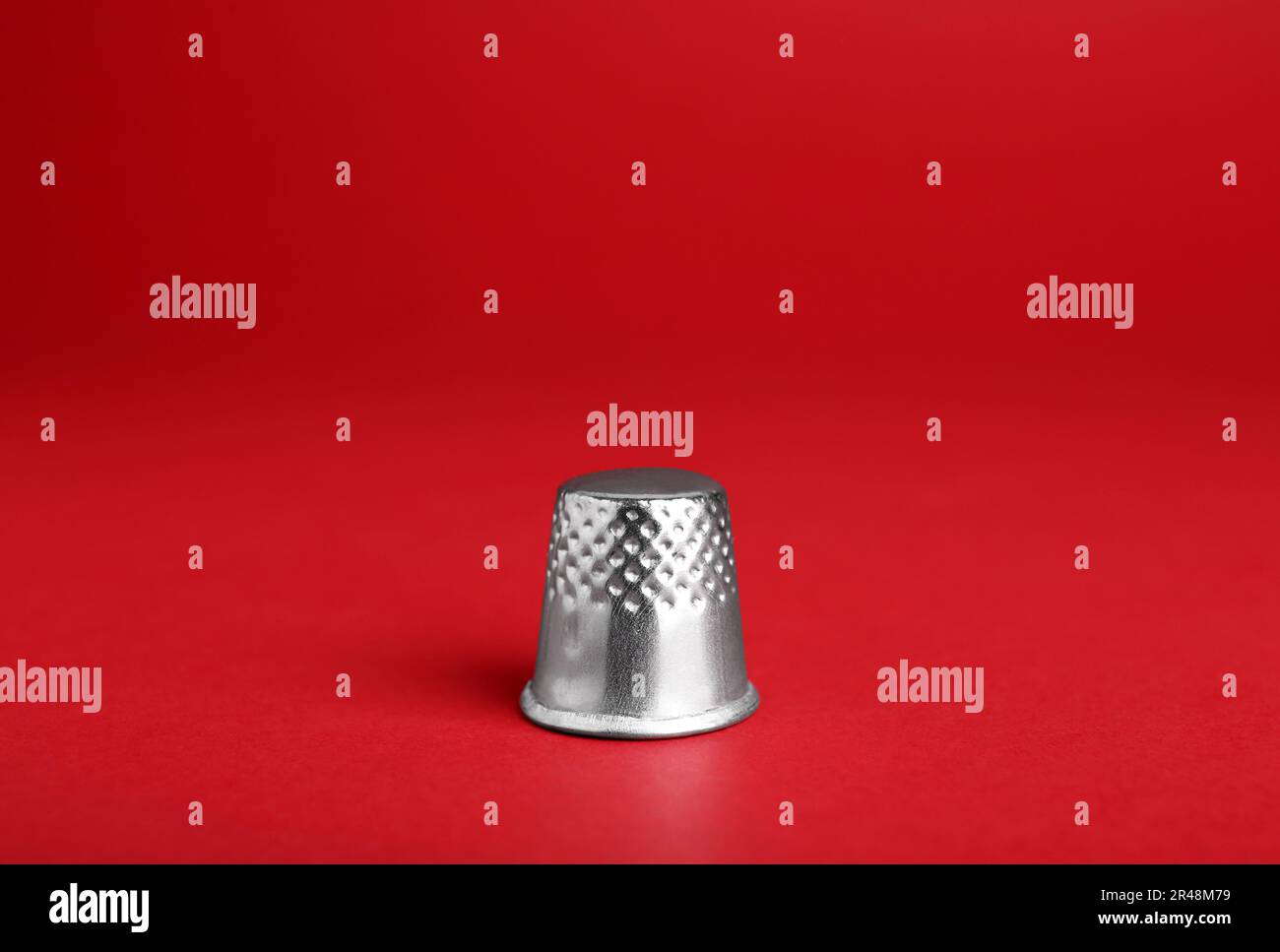 Silver thimble on red background. Sewing accessory Stock Photo - Alamy