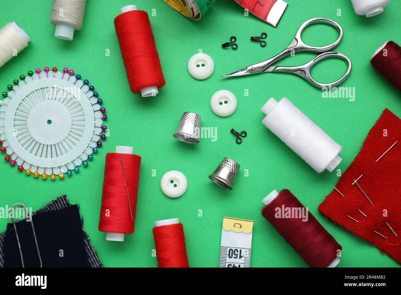 Flat lay composition with thimbles and different sewing tools on green ...