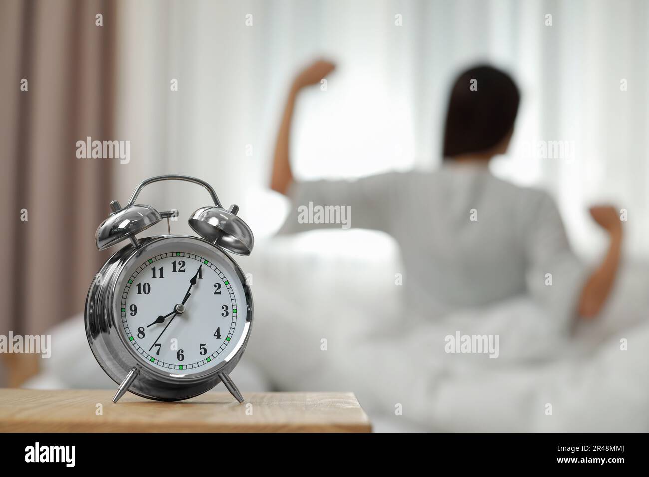 Woman stretching in bedroom, focus on alarm clock. Space for text Stock ...