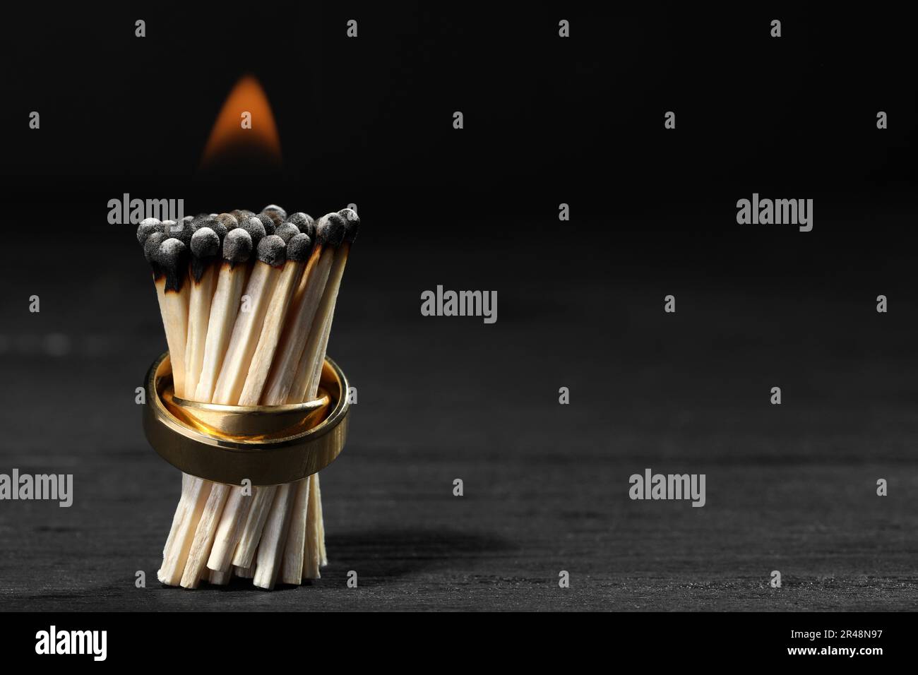 Burning matches with gold wedding rings on black background, closeup ...