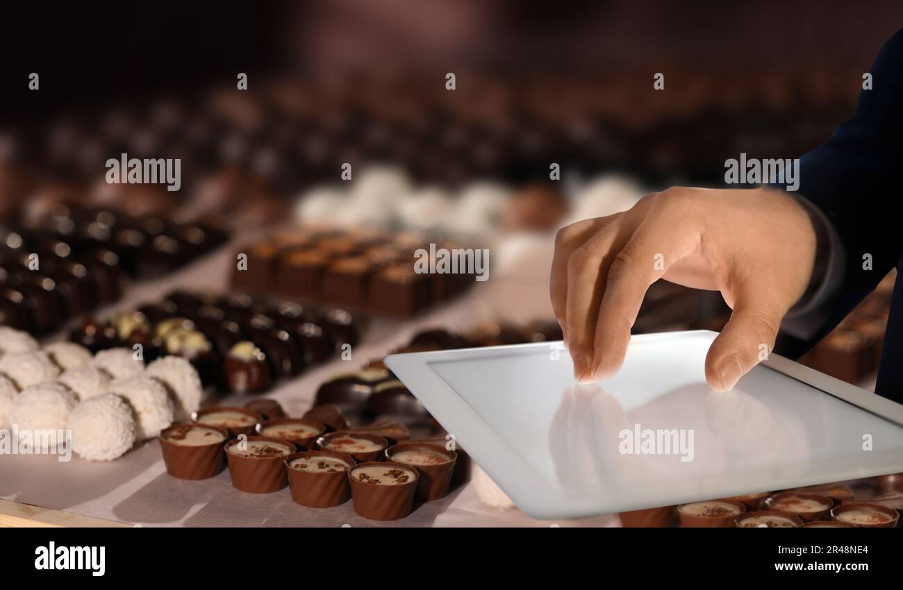 Production line of chocolate candies. Man working with tablet, closeup ...