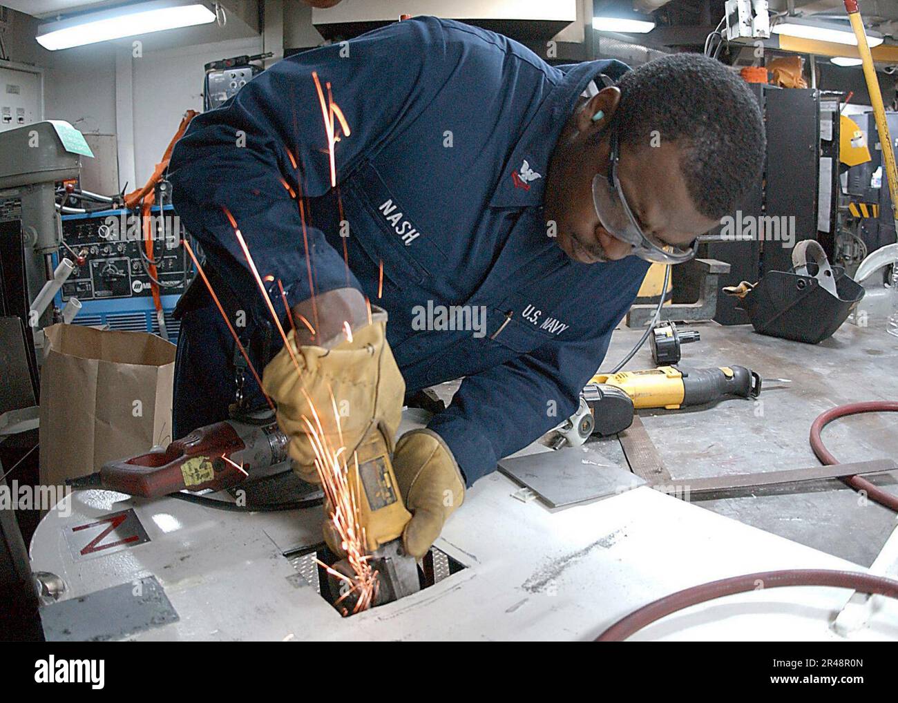 US Navy Hull Technician uses a grinder in he ships Stock Photo - Alamy