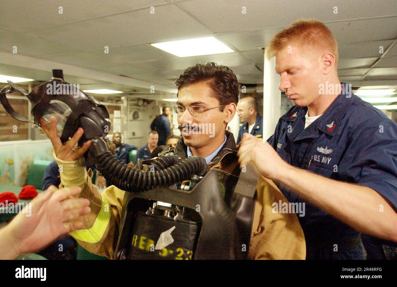 US Navy Damage Controlman assists with the firefighting gear of ...