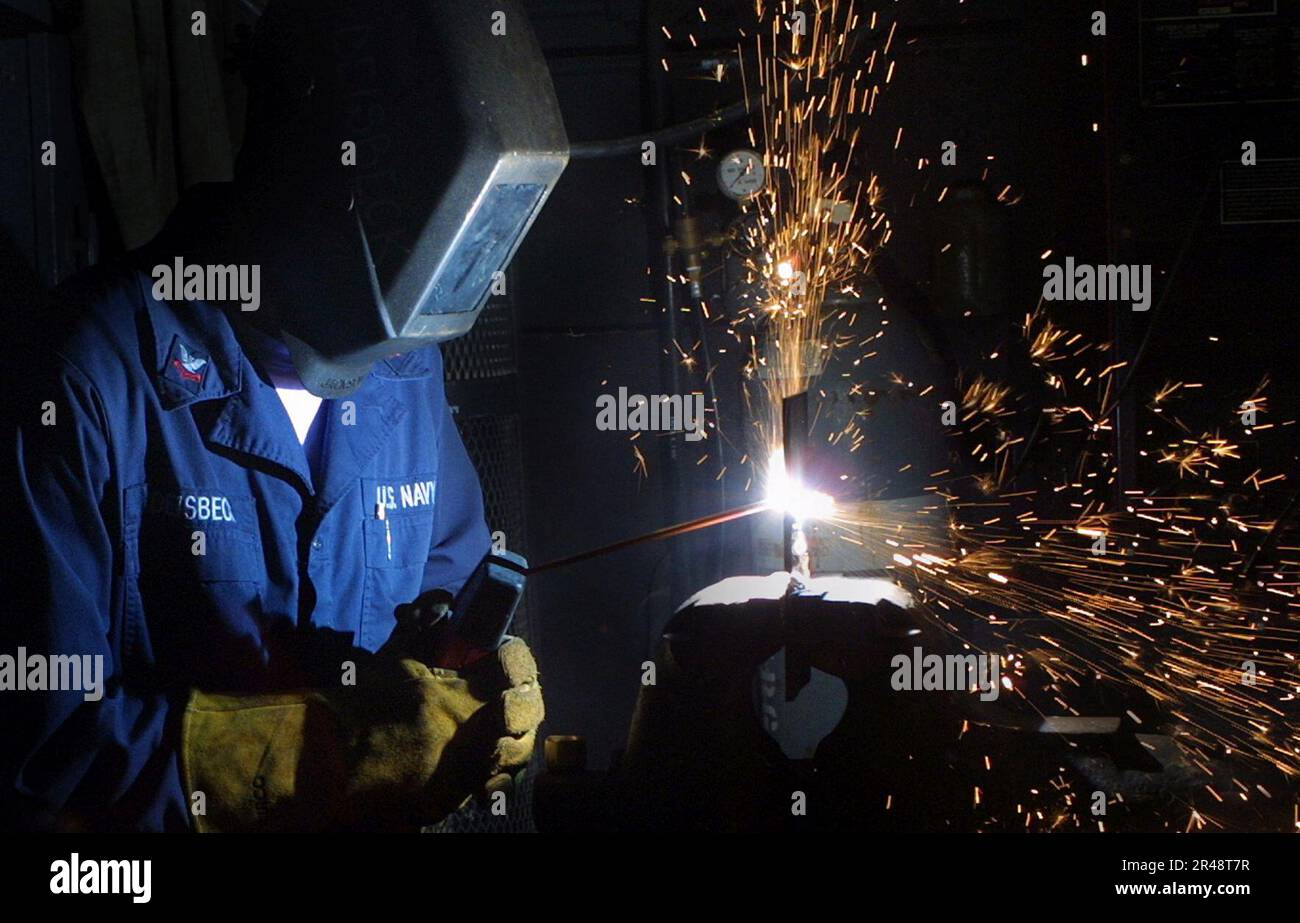 US Navy A sailor welds a steel piece of iron which will be used to make ...