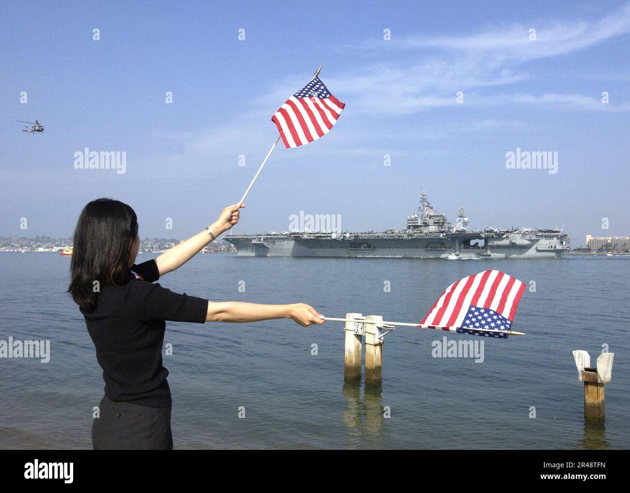 US Navy A Navy wife waves American flags as a sign of support for her ...
