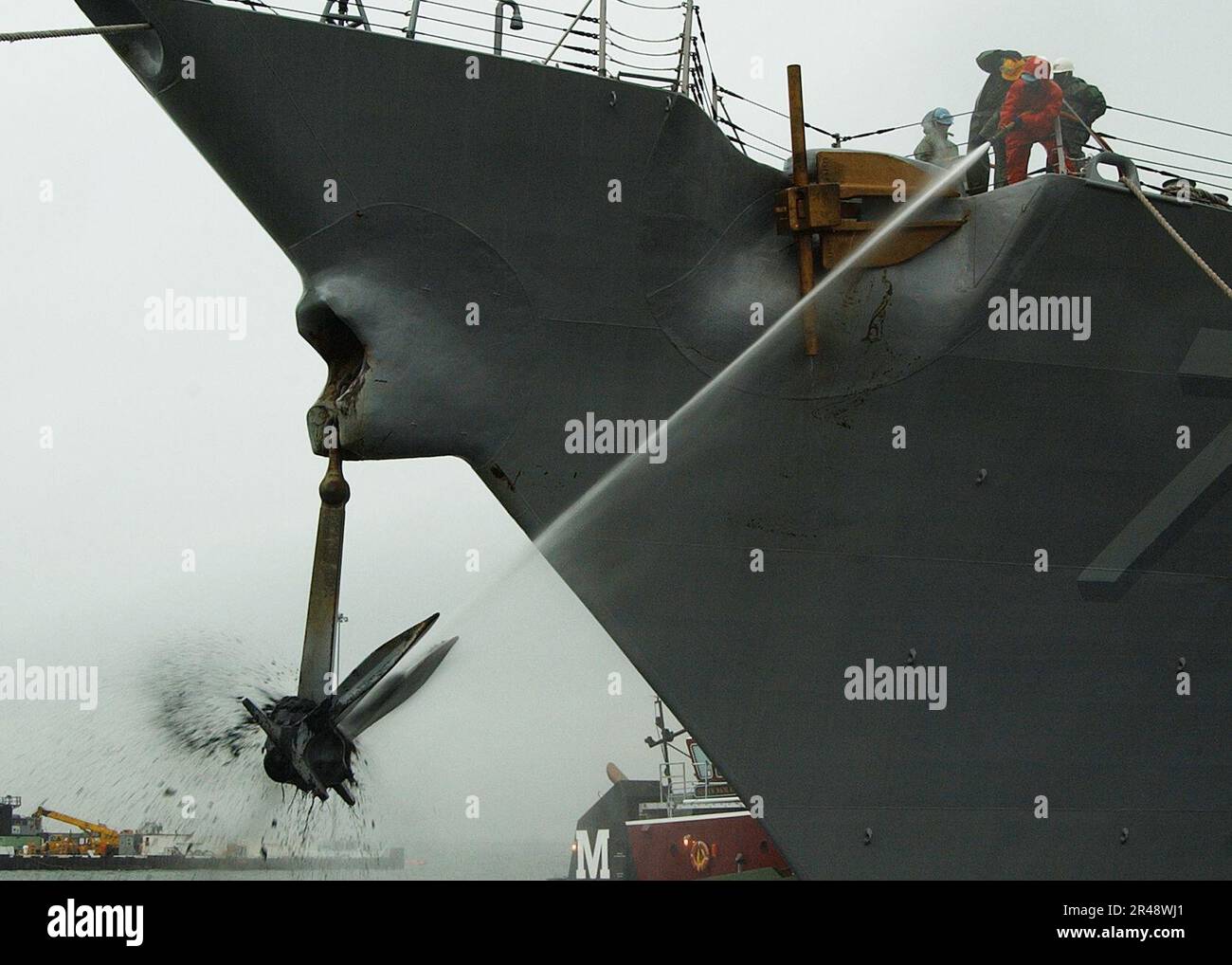 US Navy Sailor washes down the forward anchor aboard the guided missile ...